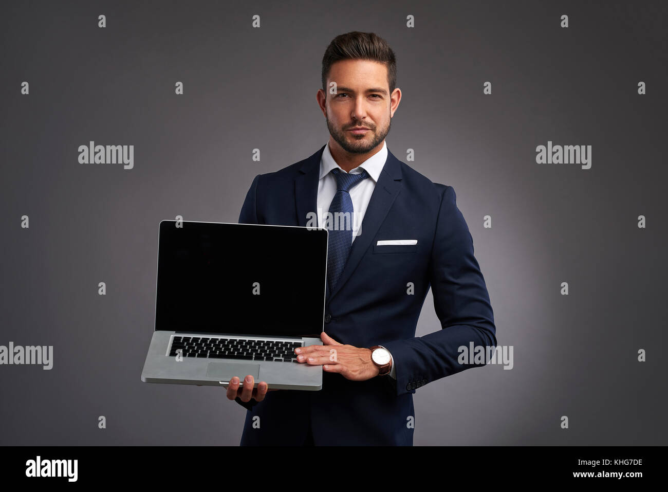 An elegant handsome young man holding and showing the screen of a ...