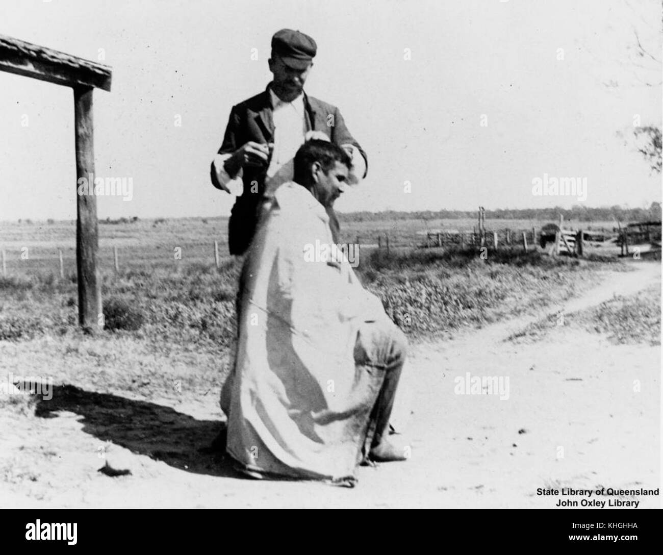 A historical photograph of a man receiving a haircut on a farm in ...