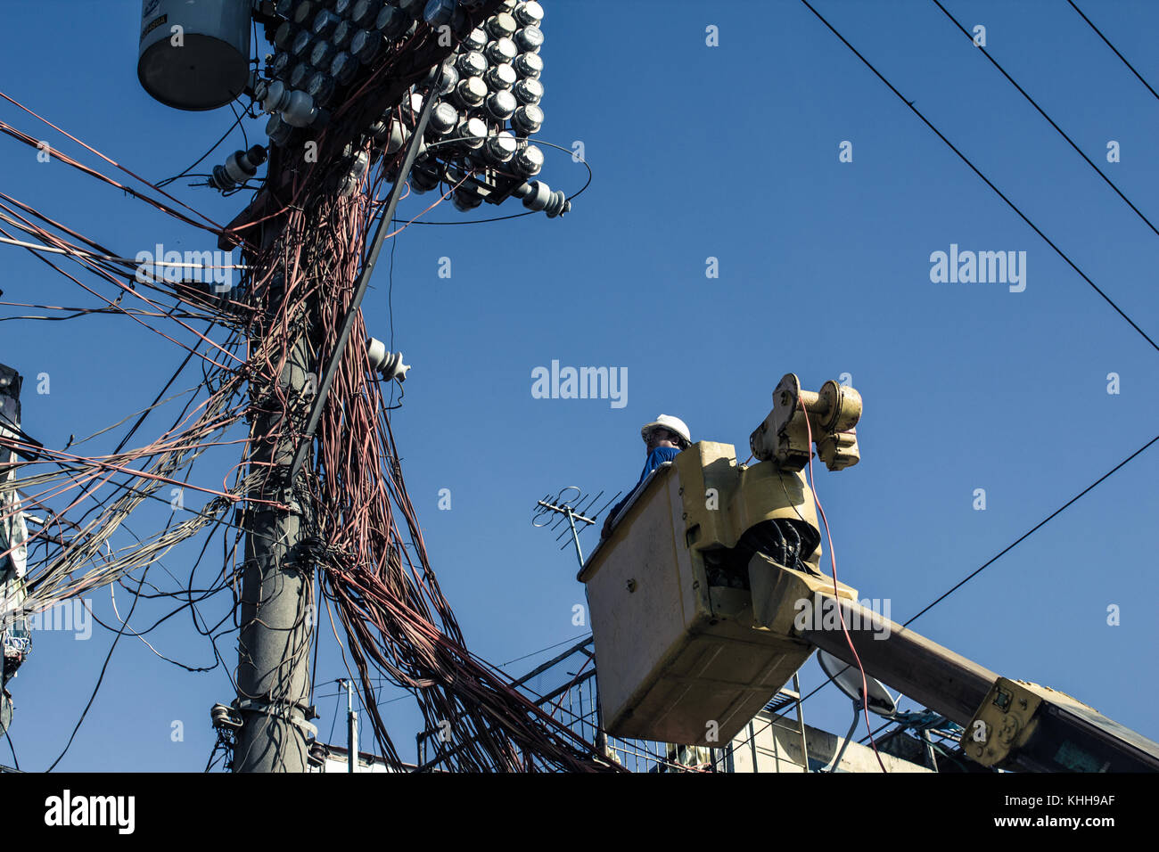 A confused electrician tries to do his job. Pole with lots of wires ...