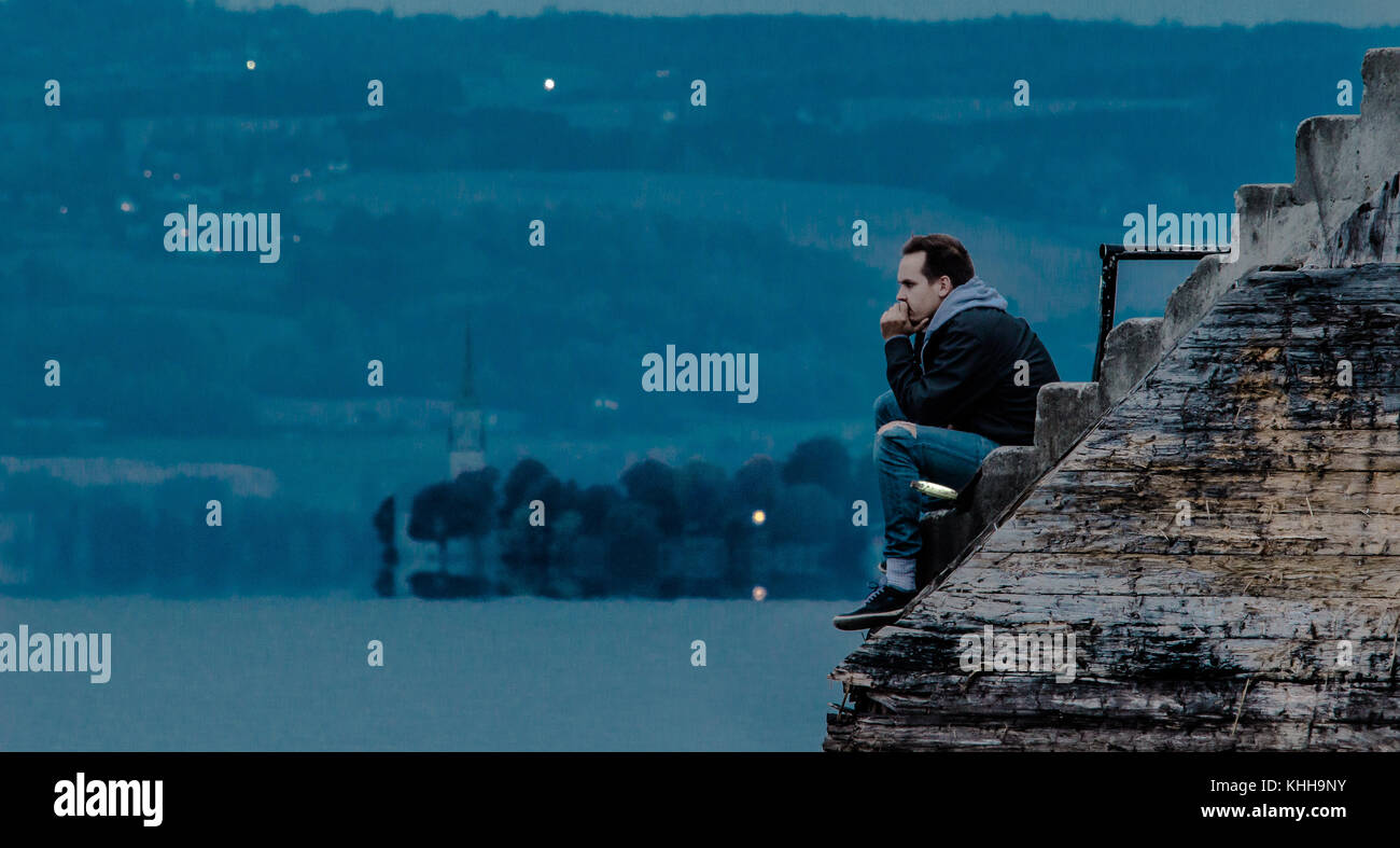 Man sitting at the dock in twilight, thinking about the meaning of life ...
