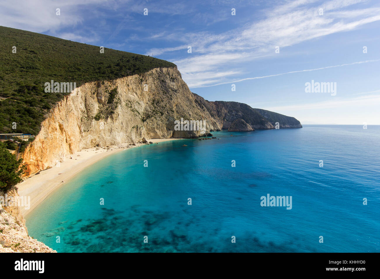 beautiful beach with blue water and big mountain with rough cliffs ...