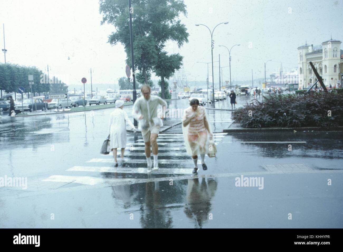 Two tourists wearing clear rain slickers and running across a cross ...