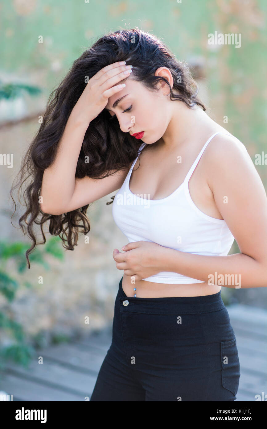 Pensive young beautiful woman hand on hair loking down outdoors Stock ...