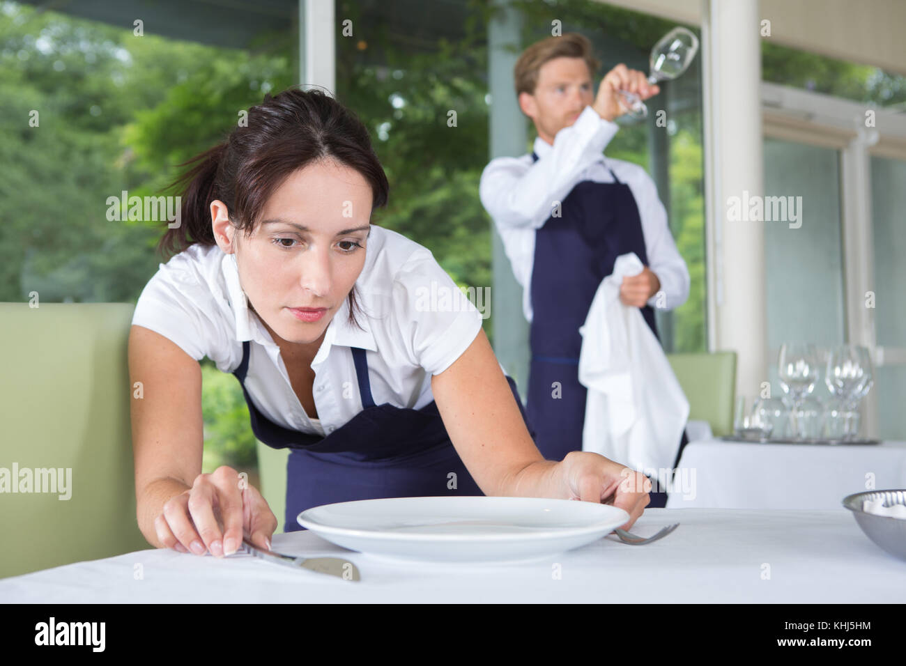 Waitress putting tableware in exact positions Stock Photo - Alamy