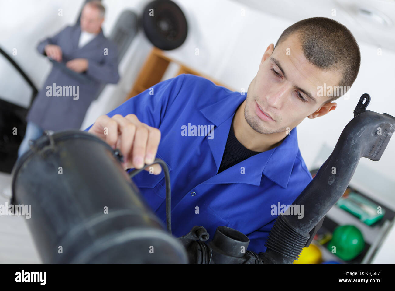 apprentice mechanic working on exhaust pipe in auto repair shop Stock ...