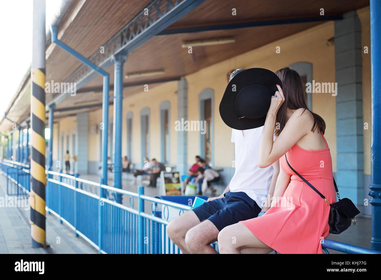 Young caucasian couple sitting on the railings at the trainstation ...
