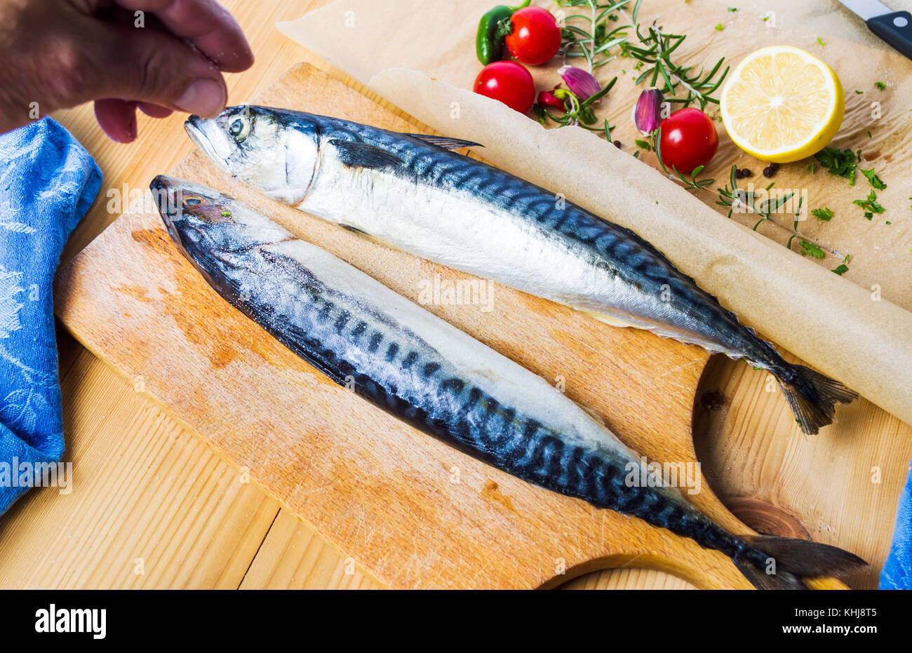 Man adding salt to fresh mackerel fish first person view Stock Photo ...