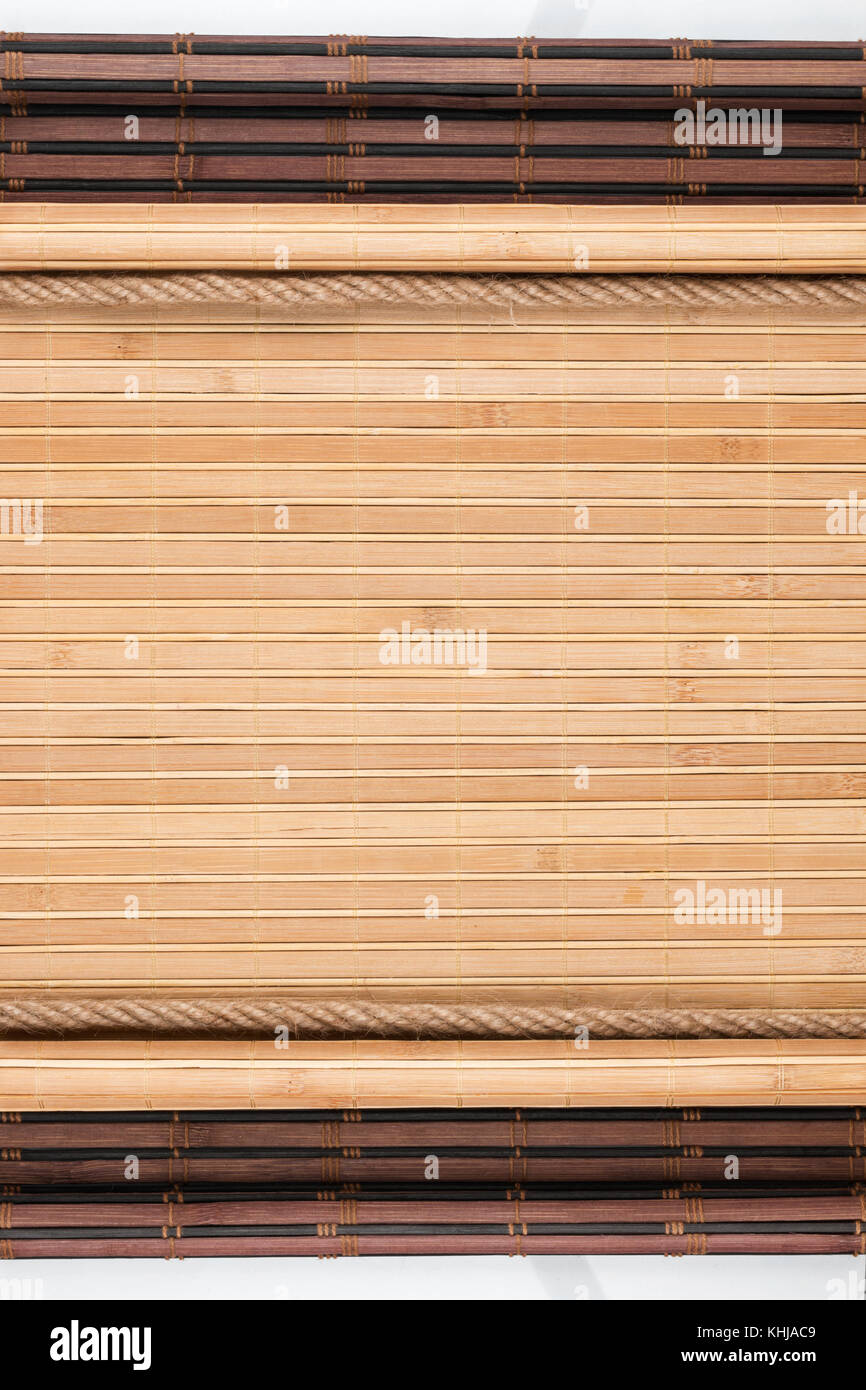 Bamboo mat with curled edges and rope, on white background. Space for ...