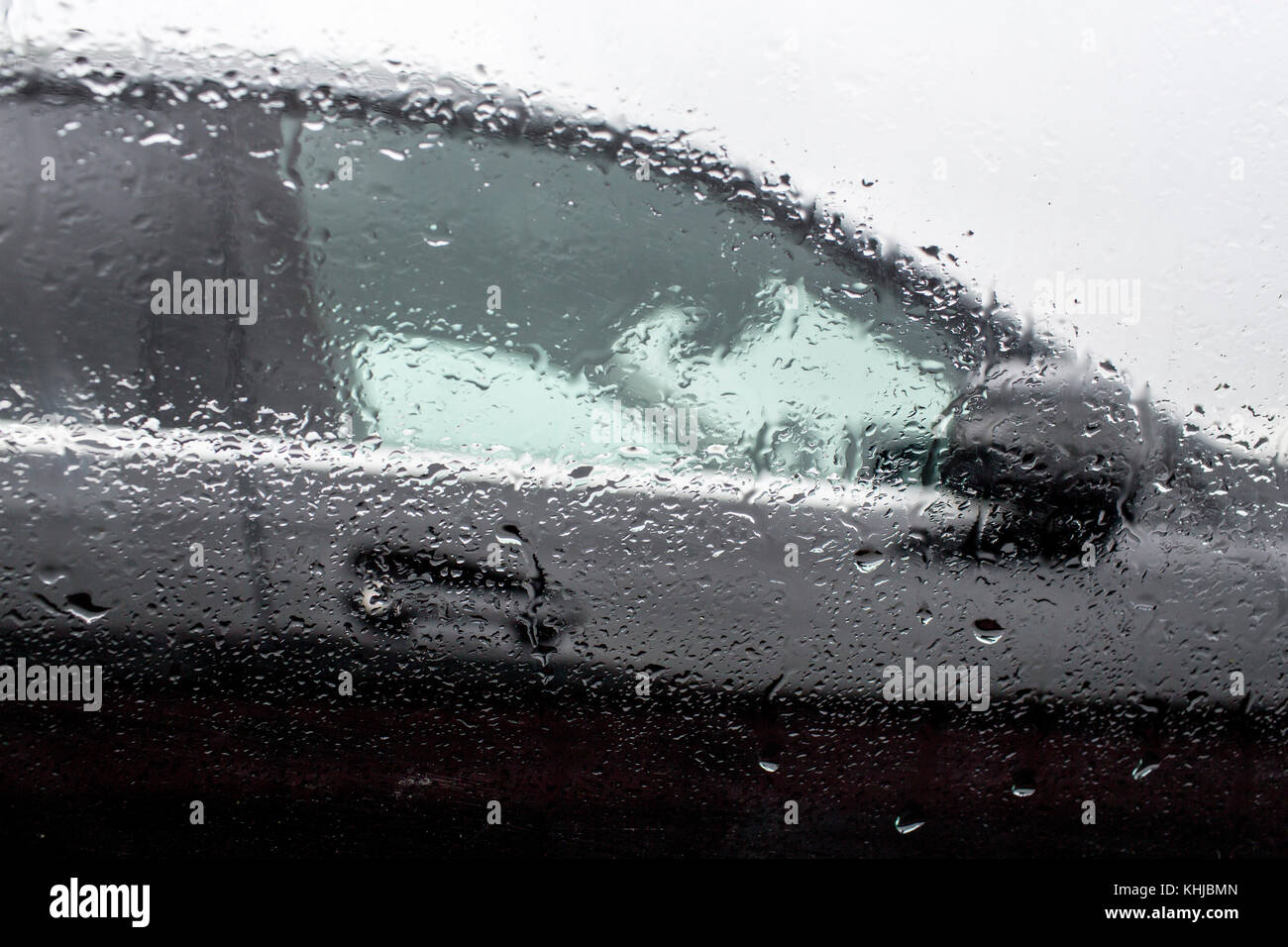 Looking out of a wet window at a parked car obsurred by the rain on the ...