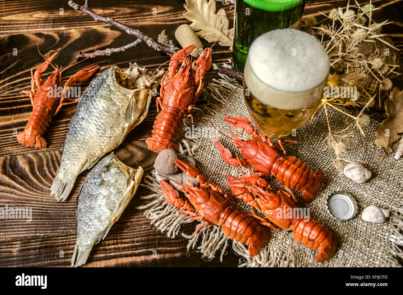 Beer with foam in glass and dried salted fish and with boiled red ...