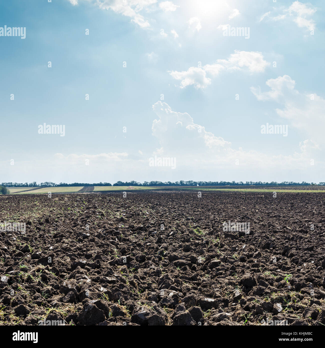 sun in clouds over black field after harvesting Stock Photo - Alamy