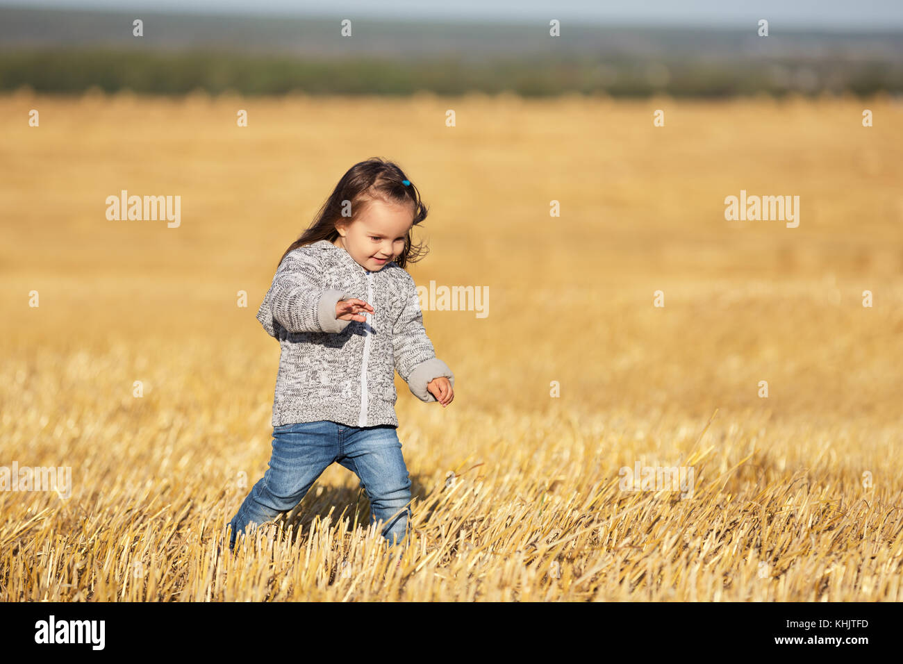 Happy 2 year old girl walking in a summer harvested field Stock Photo ...