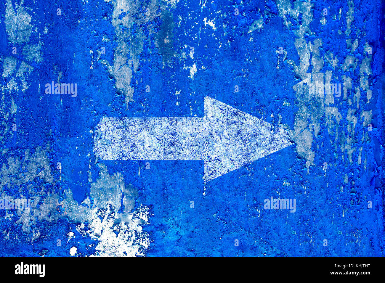 White arrow painted on old grunge and weathered blue wall texture ...