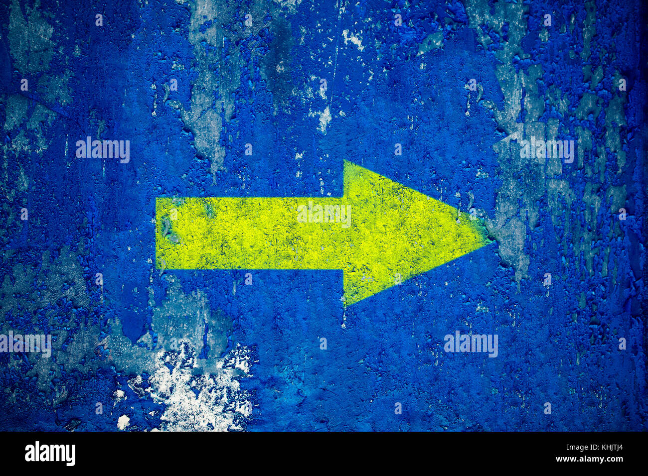 Yellow arrow painted on old grunge and weathered blue wall texture ...