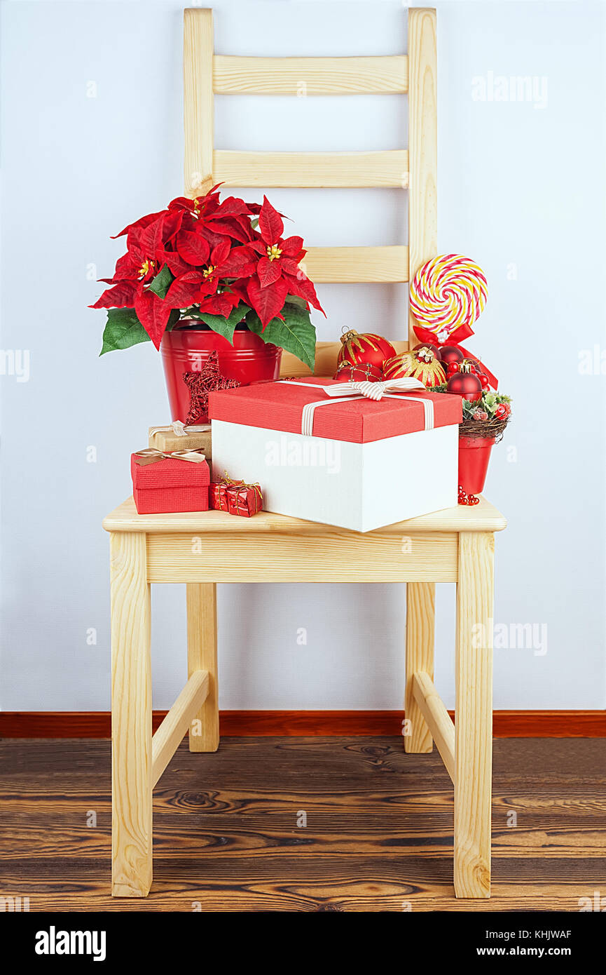 Wooden chair with Christmas decorations on a white wall background ...