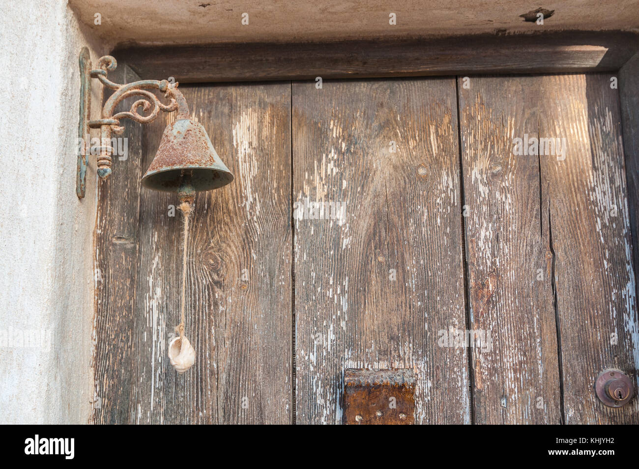 Doorbell made with an old metal bell on an old wooden door, La Graciosa ...