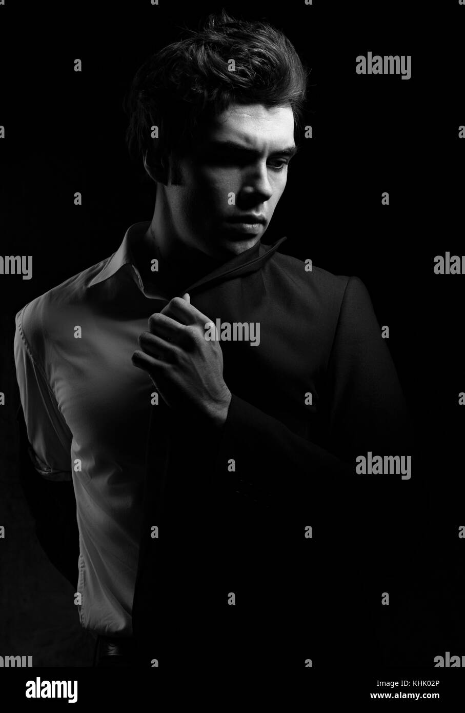 Handsome charismatic emotional man looking serious in dark shadow ...