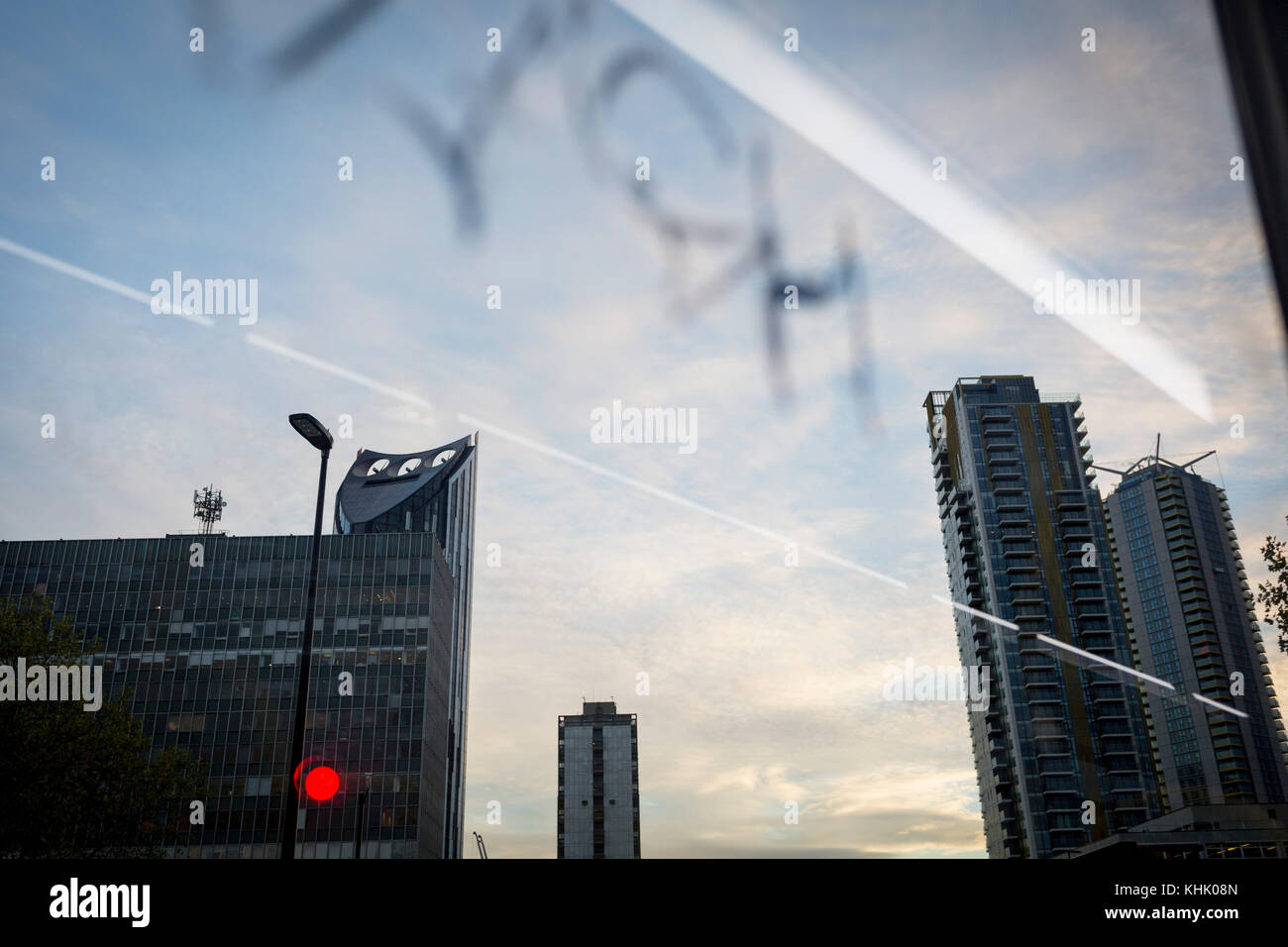 Graffiti written on the window of a London bus and urban tower blocks ...