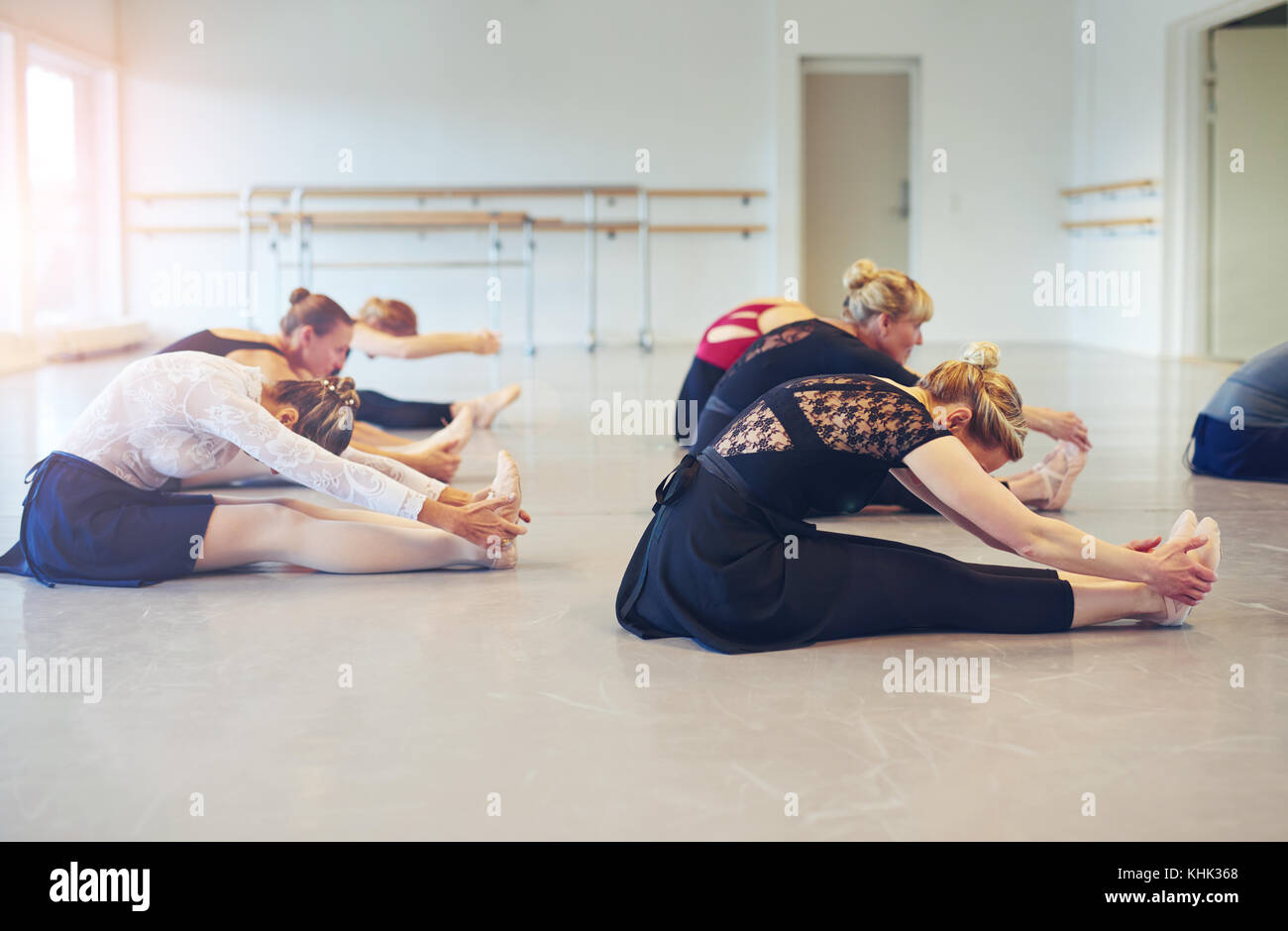 Side view of unrecognizable women dancing ballet sitting on floor and ...