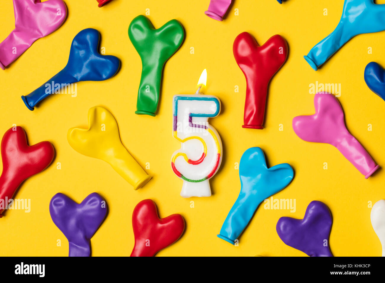 Number 5 candle with party balloons on a bright yellow background Stock ...