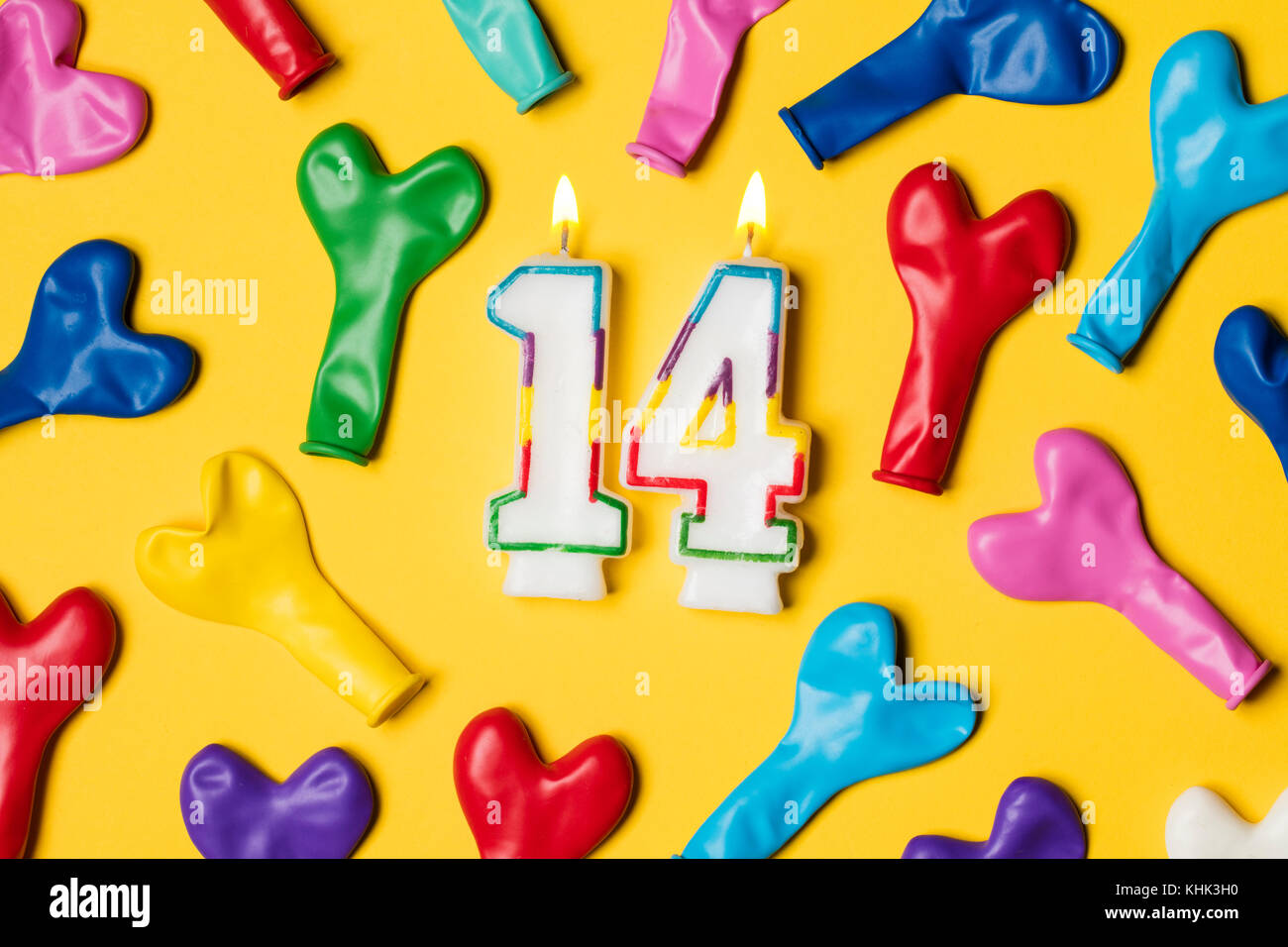 Number 14 candle with party balloons on a bright yellow background ...
