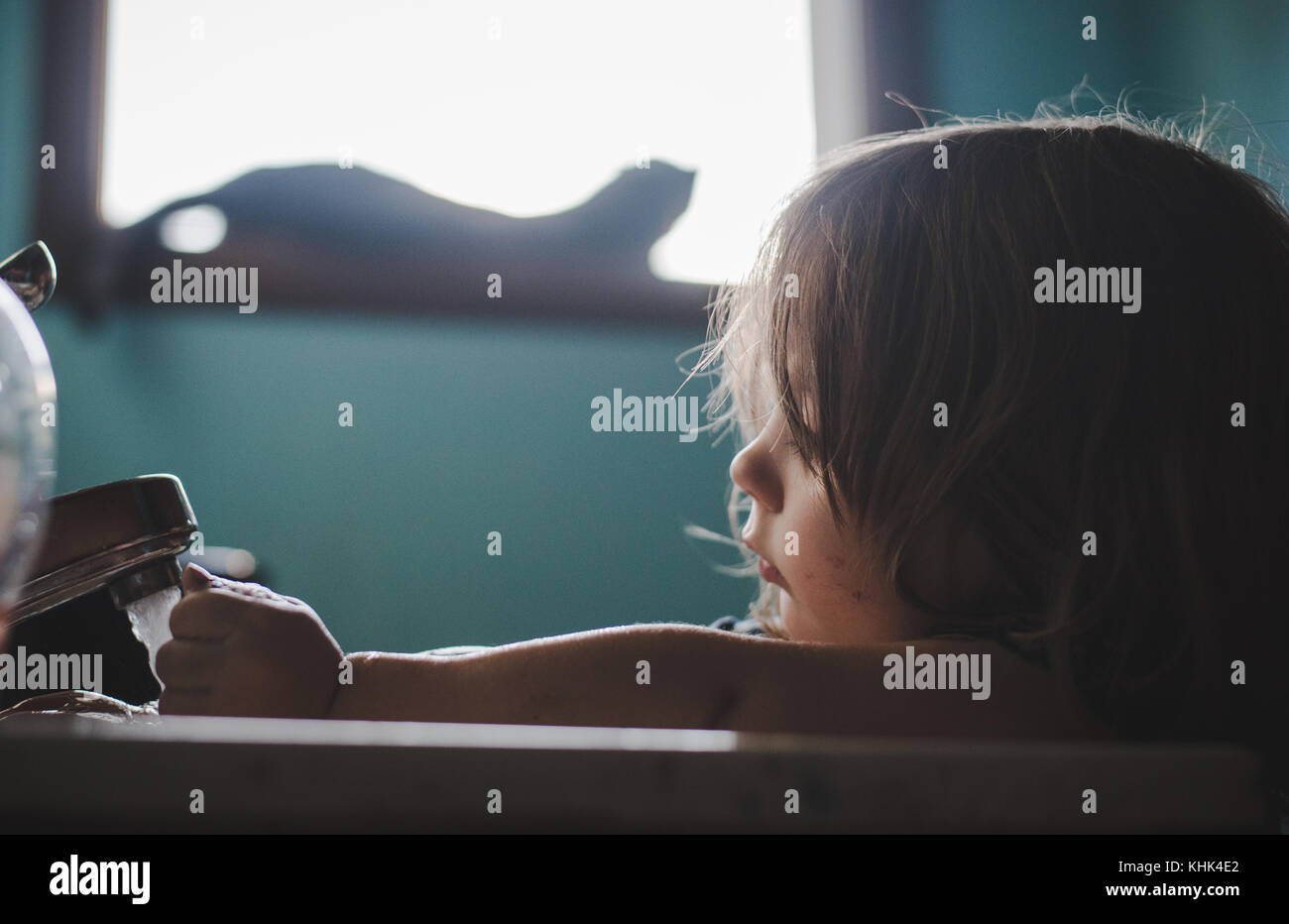A toddler girl washing paint off her hands in a bathroom sink Stock ...