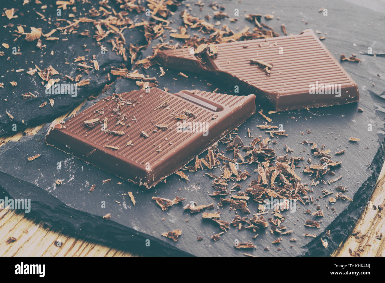 Broken dark chocolate and chocolate flakes on a wooden table Stock ...