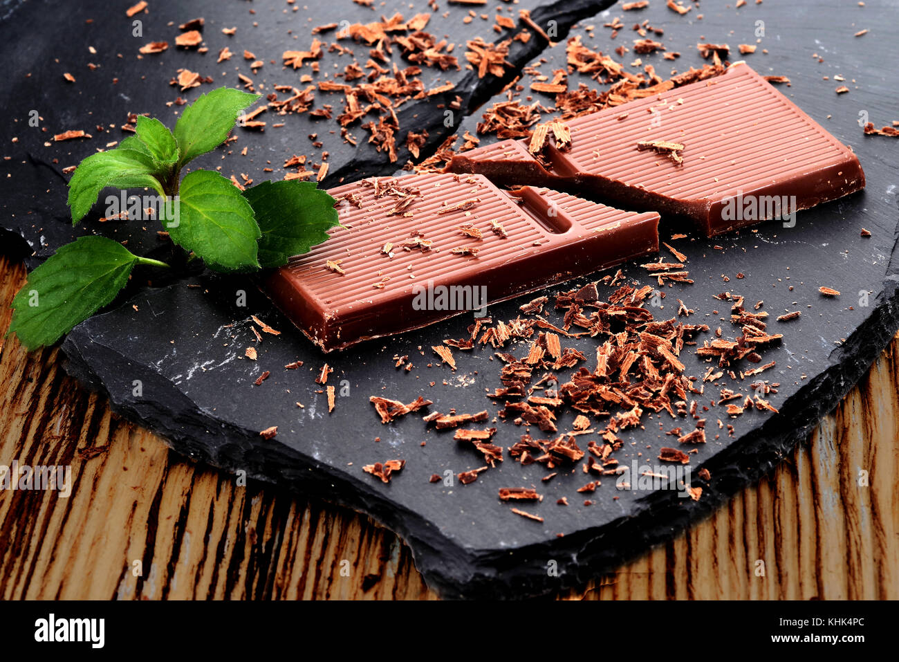 Broken dark chocolate and chocolate flakes on a wooden table Stock ...