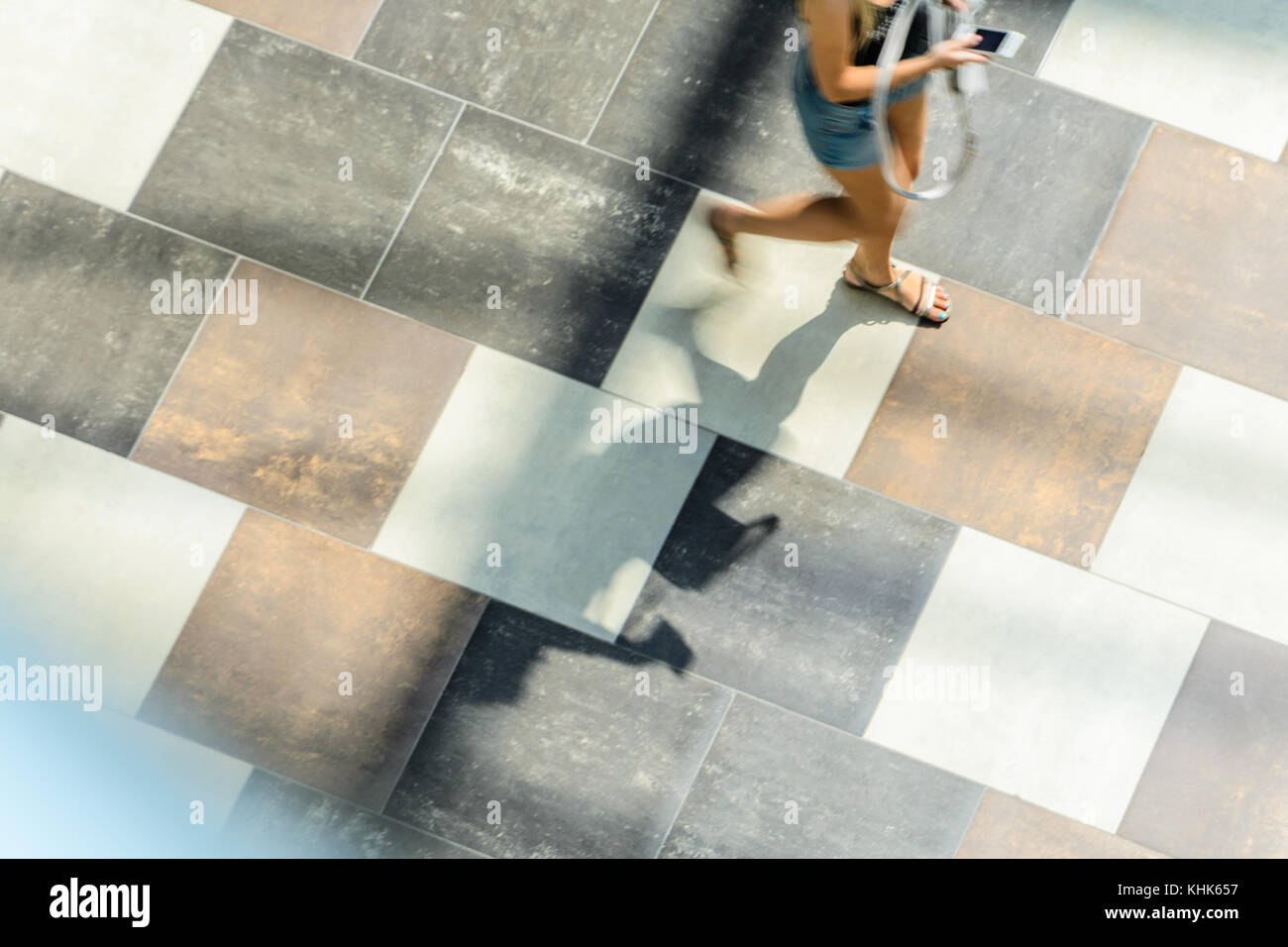 Silhouette of a walking woman with long shadow from above. Abstract ...