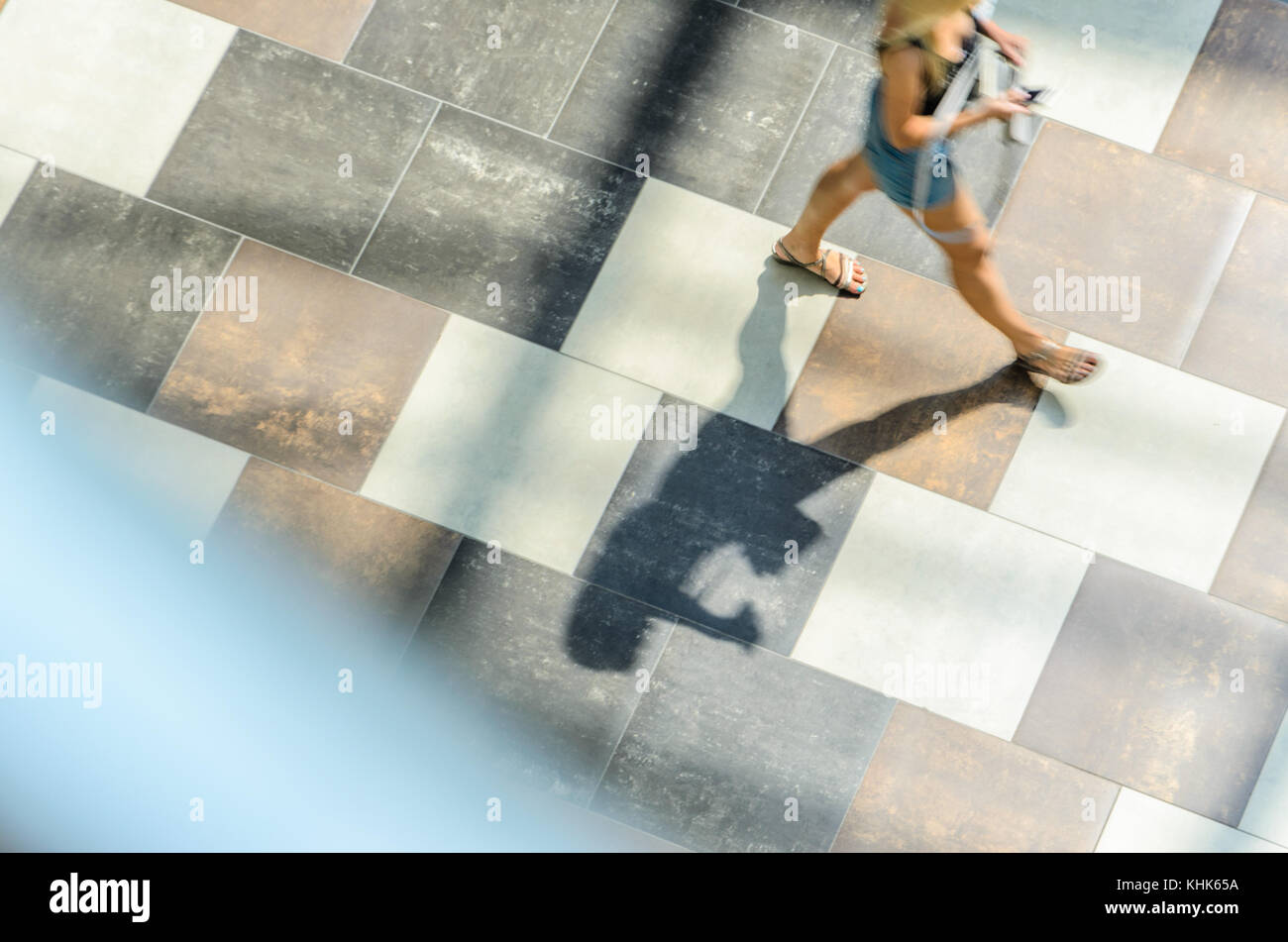 Silhouette of a walking woman with long shadow from above. Abstract ...
