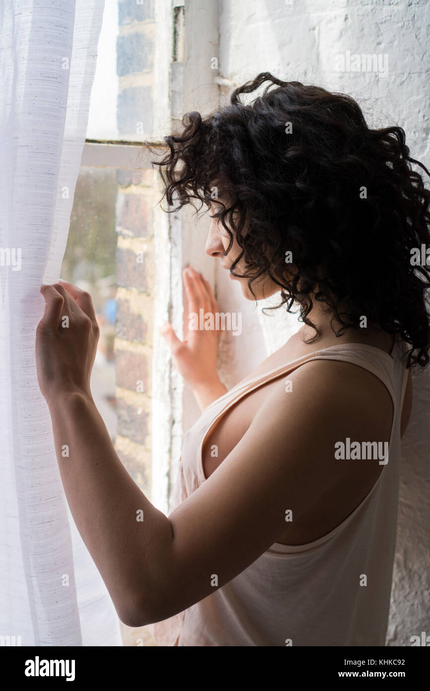 SIde view of a young woman looking out of the window Stock Photo - Alamy