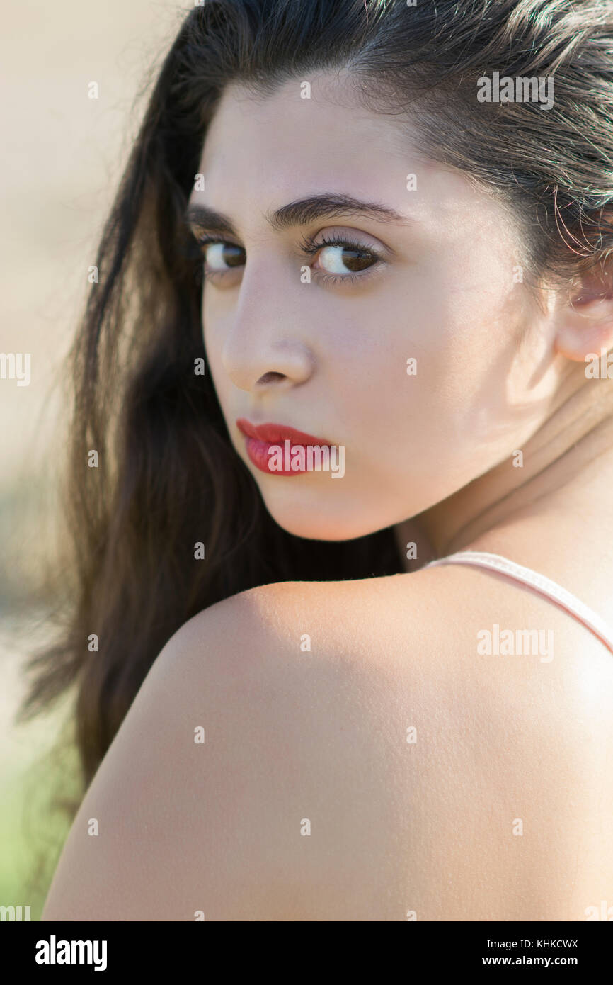 Beautiful young woman looking over shoulder outdoors Stock Photo - Alamy