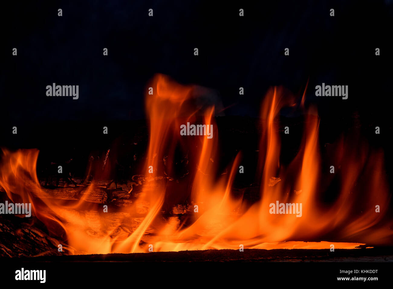 Red and orange spurts of flame and coal from the bonfire on a black ...