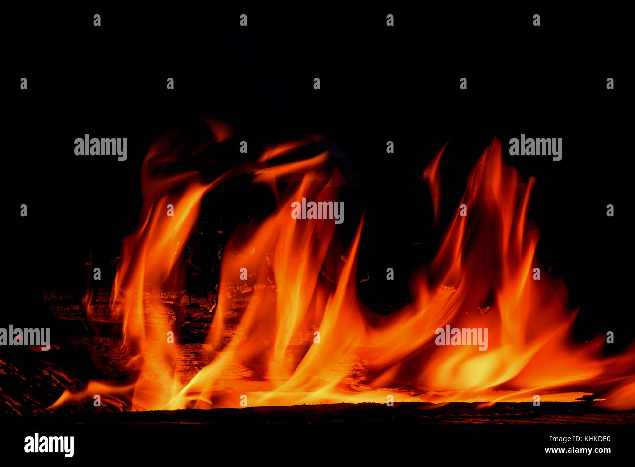 Red and orange spurts of flame and coal from the bonfire on a black ...