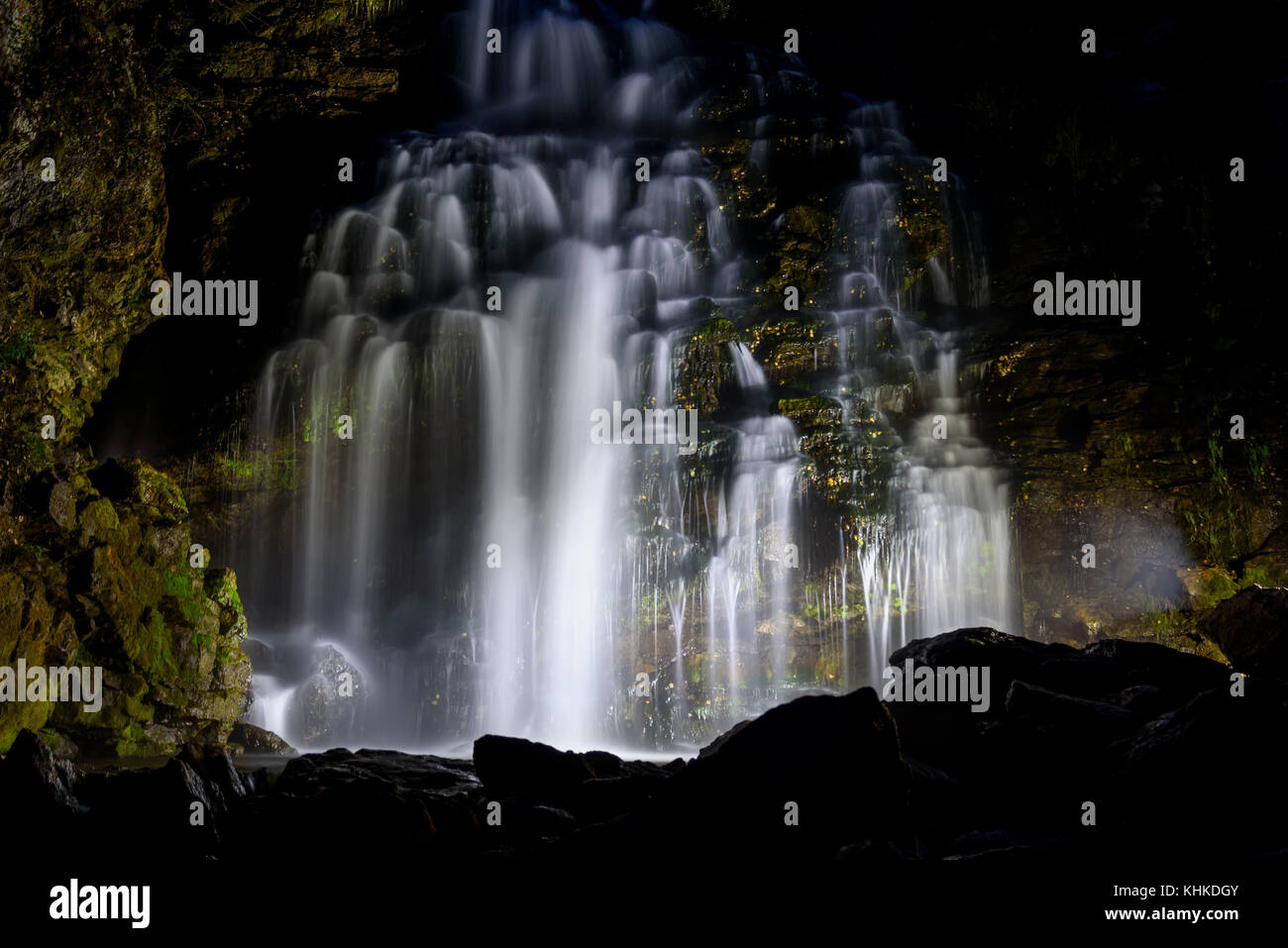 Beautiful night view of the waterfall with backlight among the rocks ...