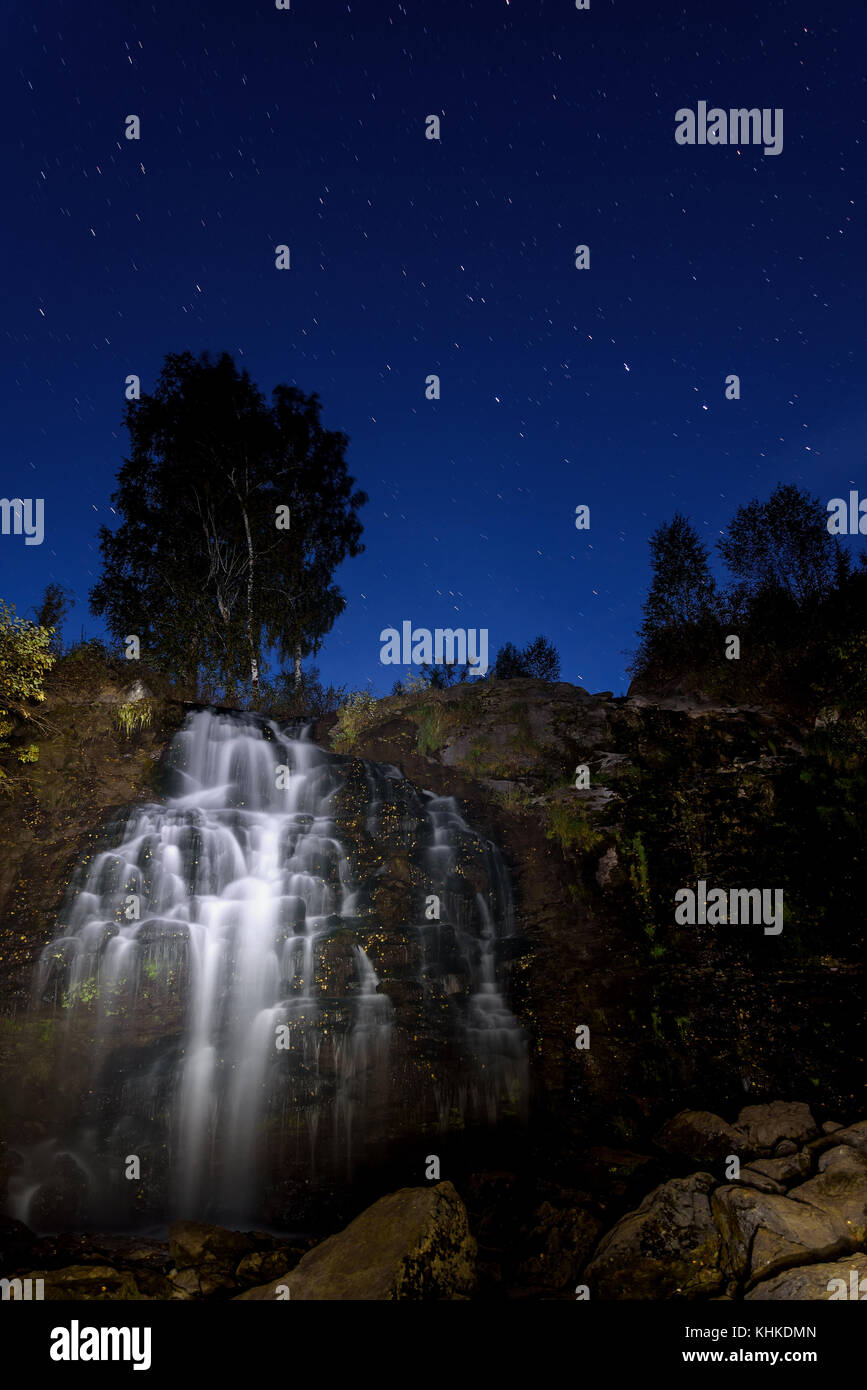 Beautiful night landscape with a waterfall illuminated among the rocks ...