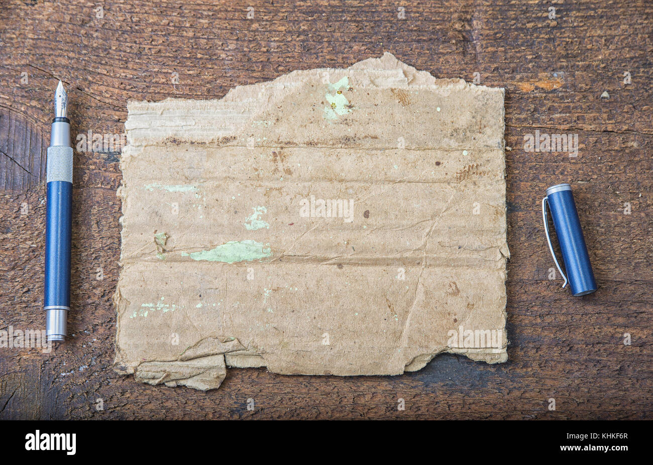 Torn piece of old paper for message or word of wisdom with pen on brown ...