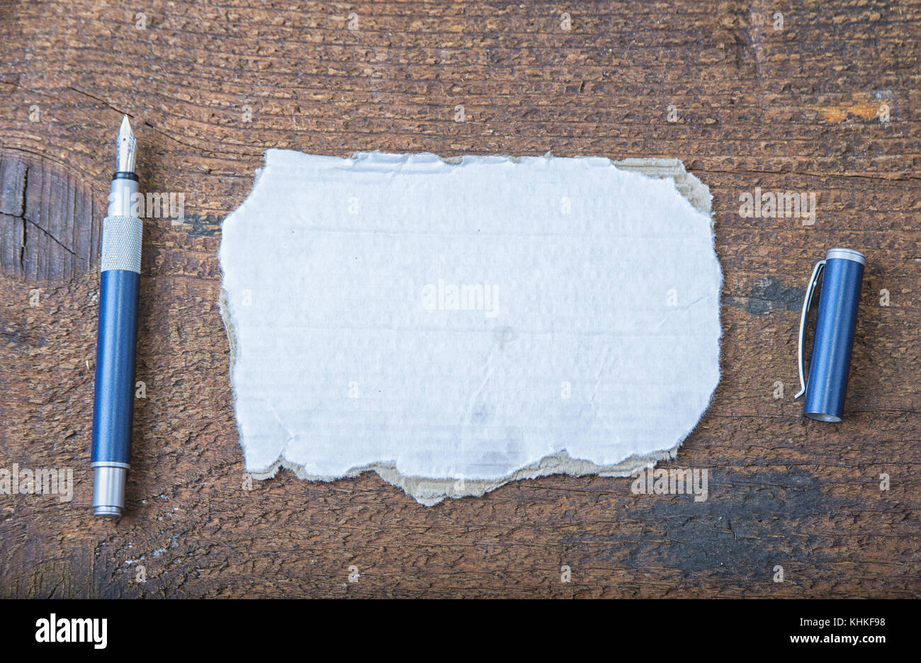 Torn piece of old paper for message or word of wisdom with pen on brown ...