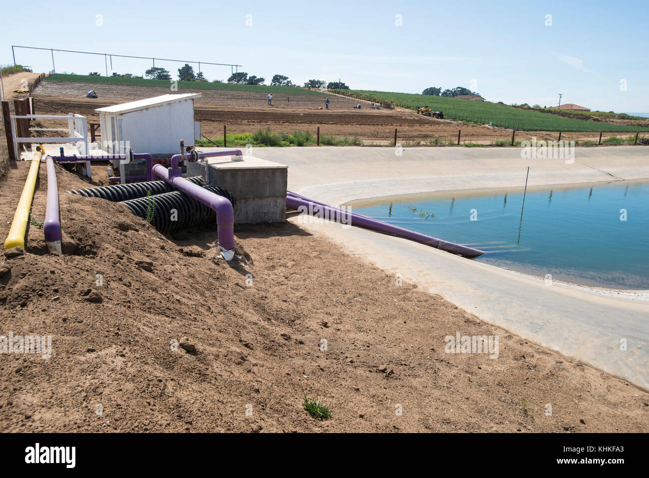 The plastic lined pond, in the background, receives rain water from a ...