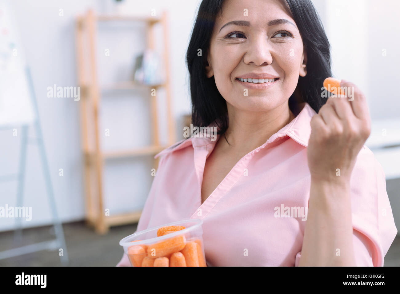 Positive delighted brunette eating carrot Stock Photo - Alamy