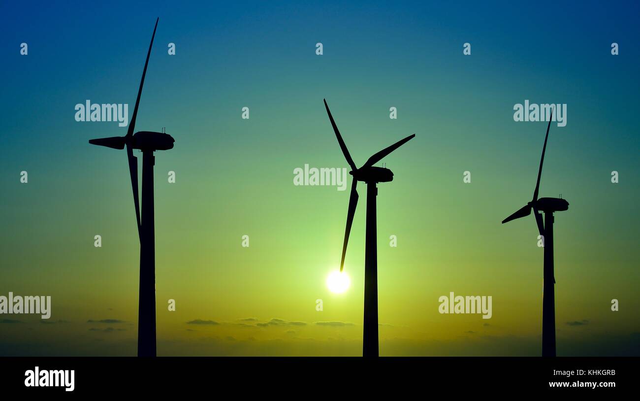 Intense sunrise, wind turbines in foreground and vivid sky background ...