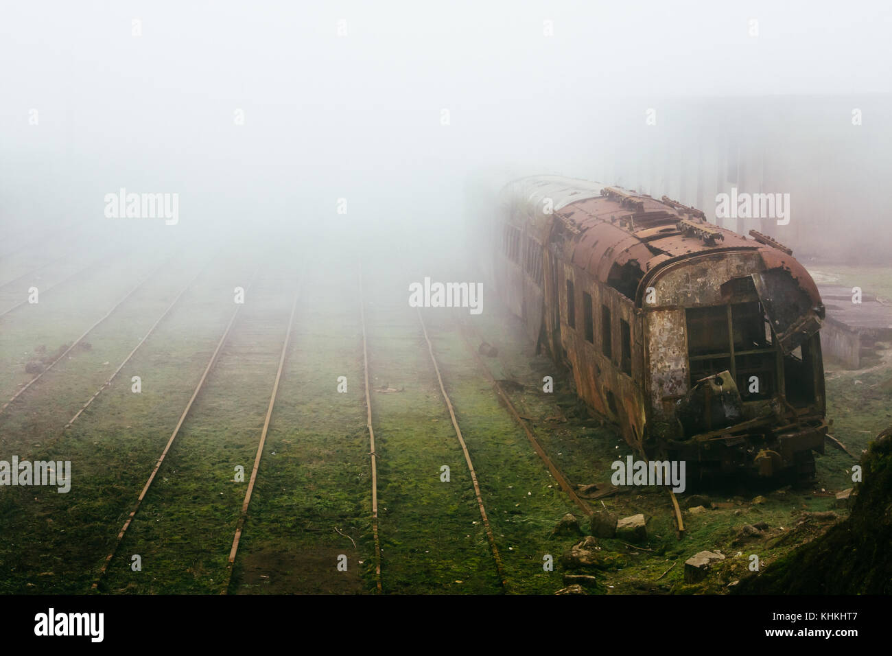 Abandoned rusting train and empty train tracks photographed in a foggy ...