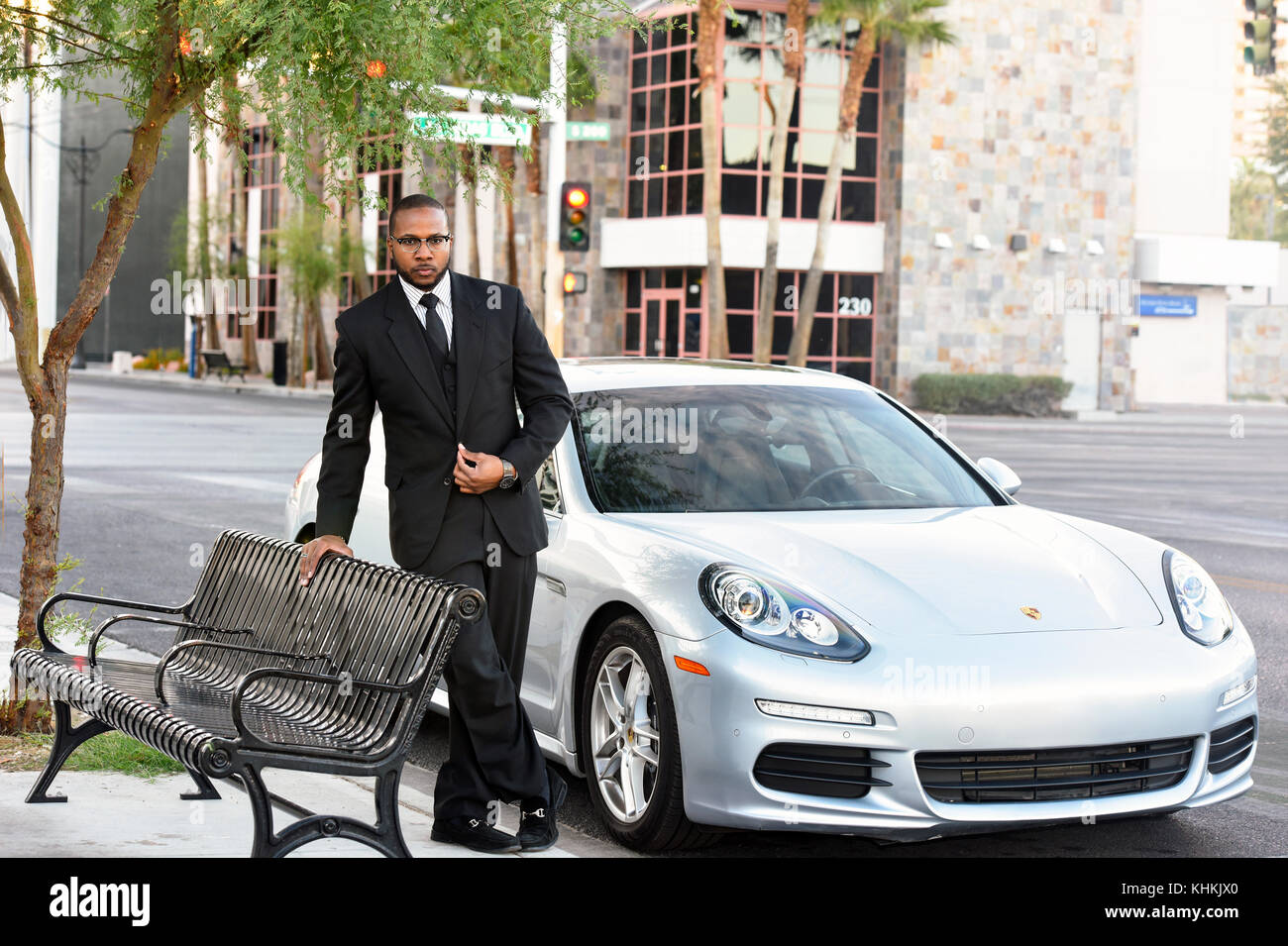 Black American businessman next to luxury car on a downtown street ...