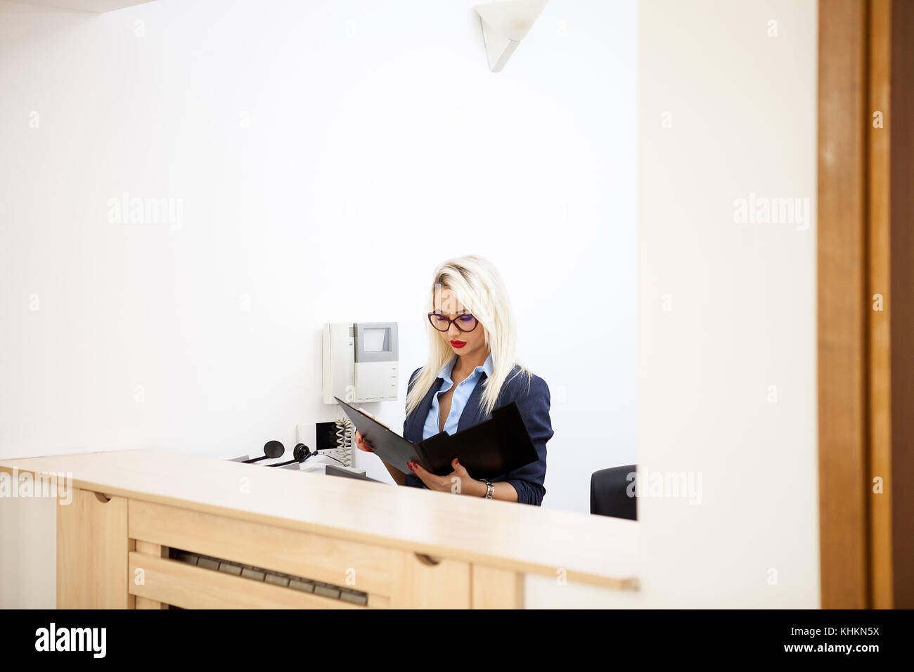 Beautiful blonde secretary looking at folder with documents Stock Photo ...