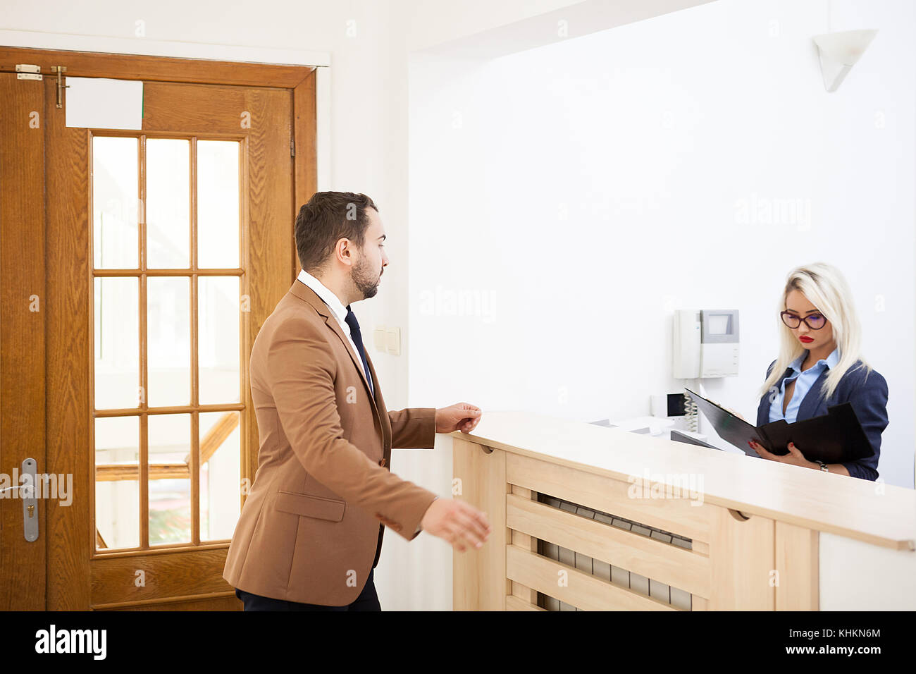 Businessman in office reception area talking with secretary Stock Photo ...