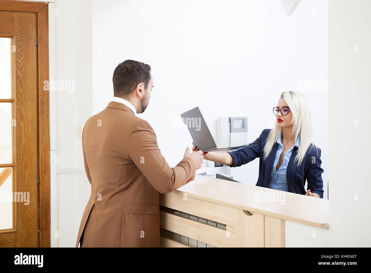 Businessman in office reception area talking with secretary Stock Photo ...