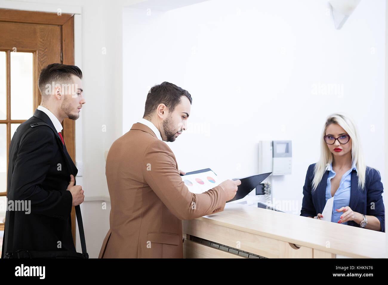 Businessman in office reception area talking with secretary Stock Photo ...