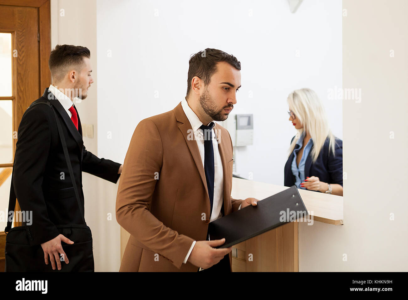 Businessman in office reception area talking with secretary Stock Photo ...
