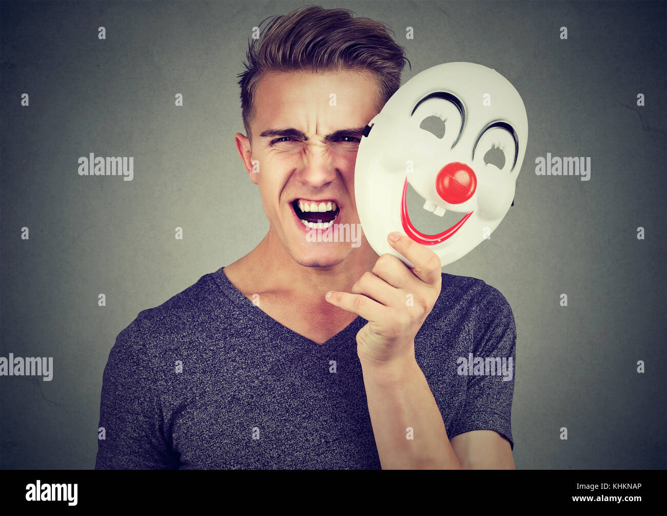 Portrait angry screaming man taking off a clown mask expressing ...