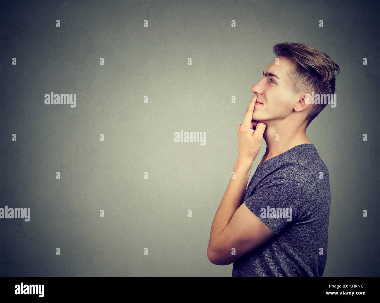 Side profile of a thoughtful young man making up his mind looking up ...